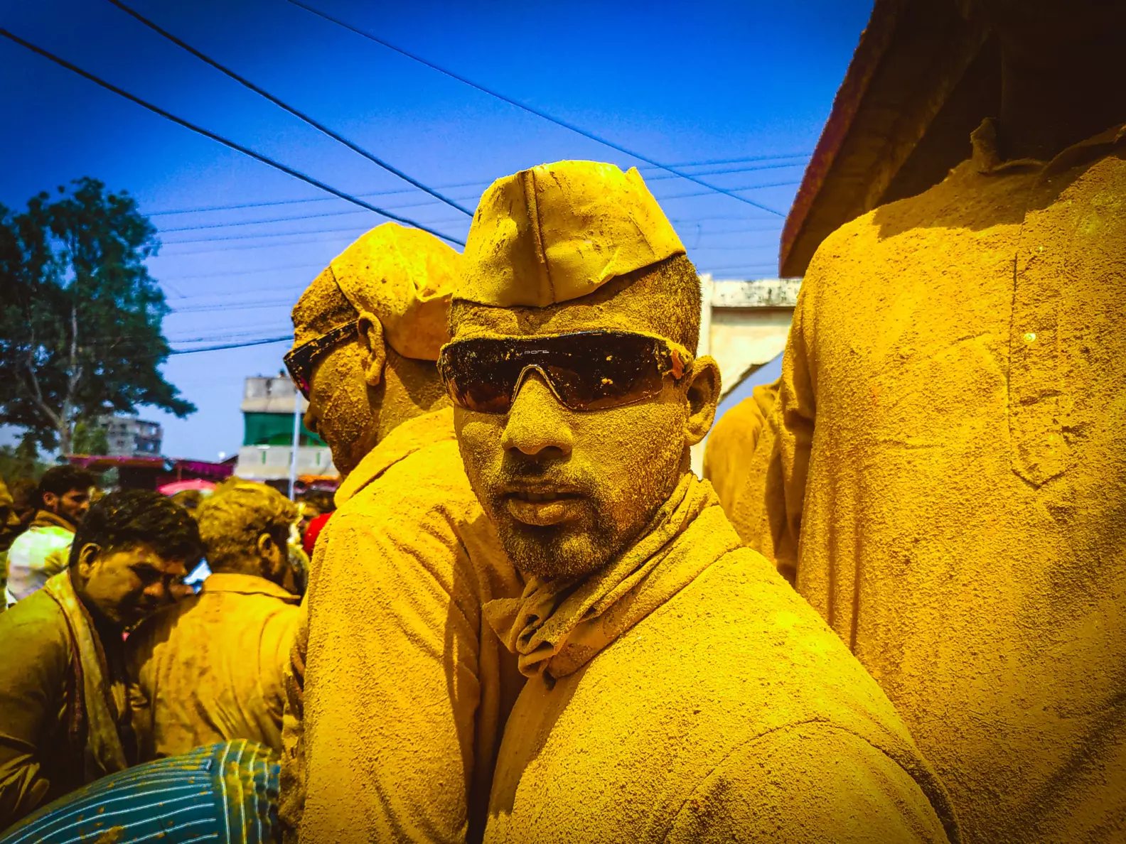 A man covered in vibrant yellow turmeric powder participates