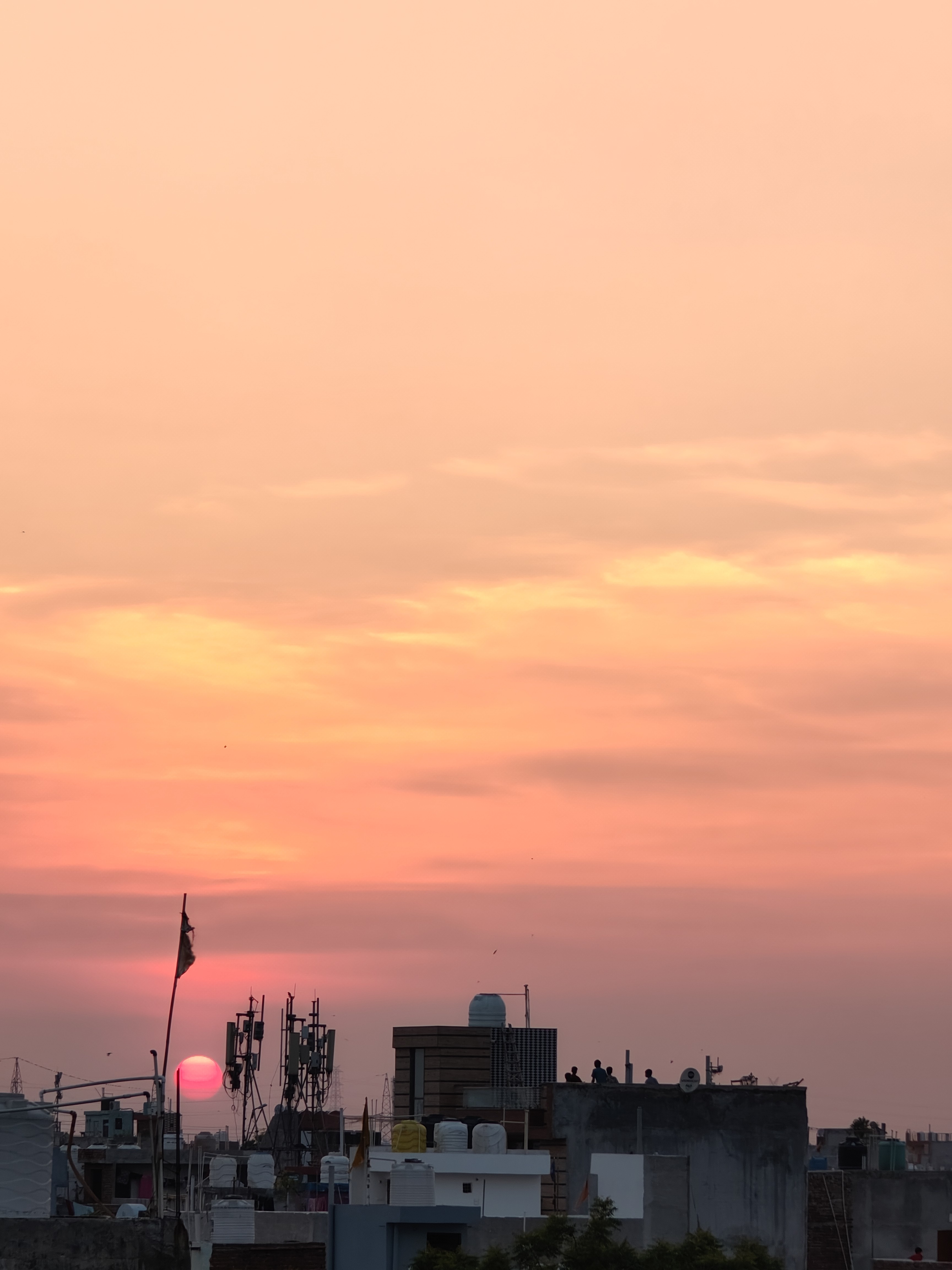 A crimson sun sinks behind the city skyline, draping rooftop